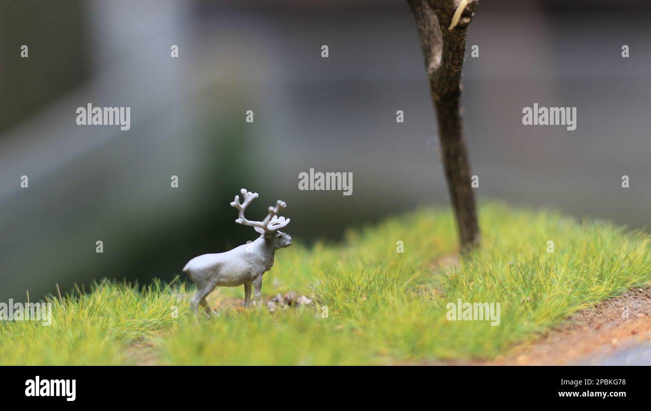 miniature figure of a moose eating. a meadow and tree diorama. concept ...