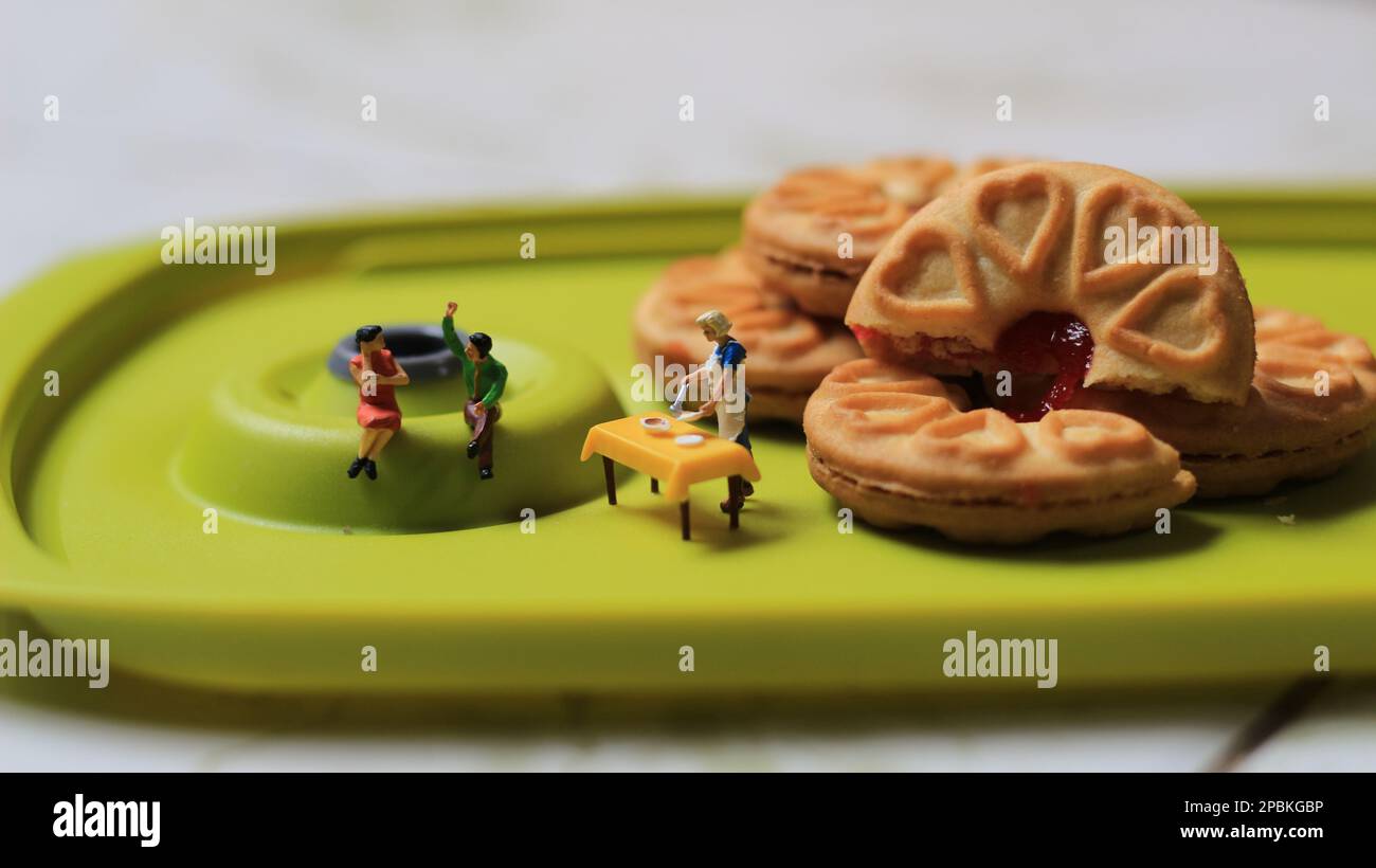 Miniature figures of a couple talking on a green dining table near a ...