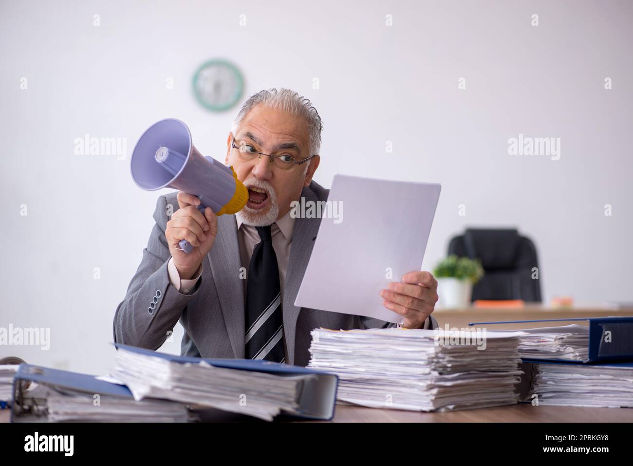 Old male boss holding megaphone at workplace Stock Photo - Alamy