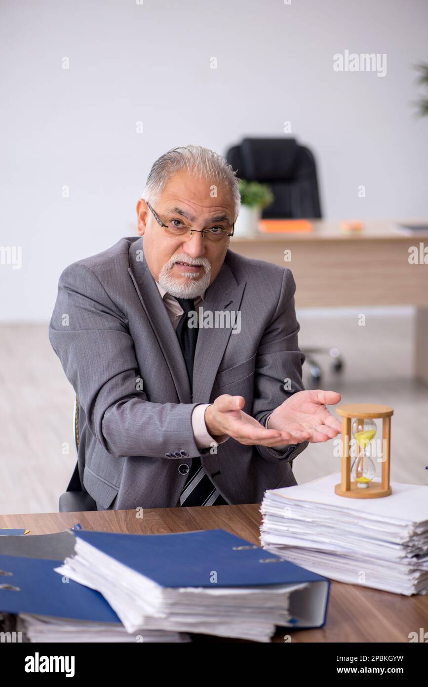 Old male boss in time management concept Stock Photo - Alamy