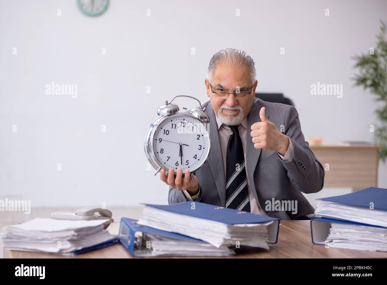 Old male boss in time management concept Stock Photo - Alamy
