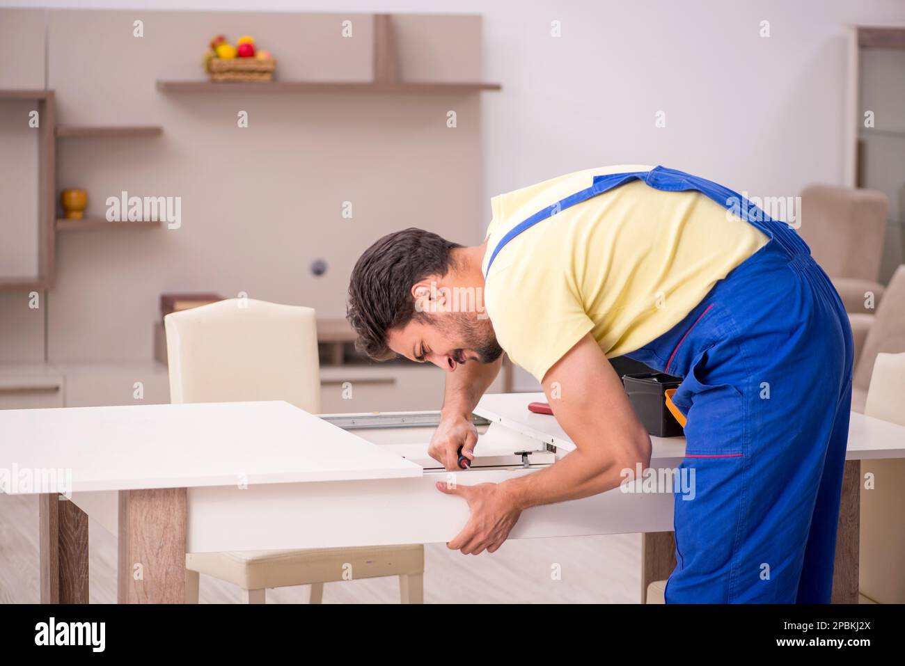 Young carpenter repairing table at home Stock Photo - Alamy