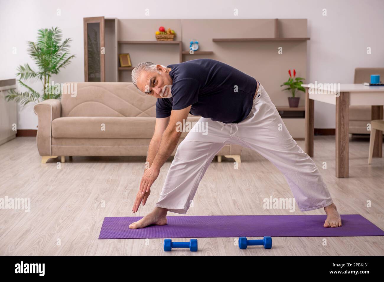 Old man doing sport exercises indoors Stock Photo - Alamy