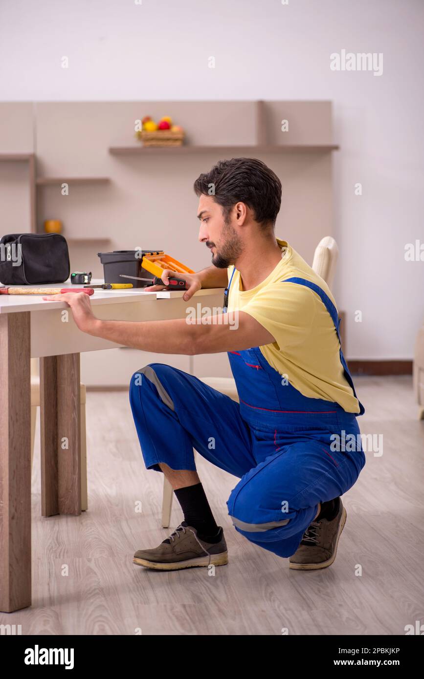 Young carpenter repairing table at home Stock Photo - Alamy