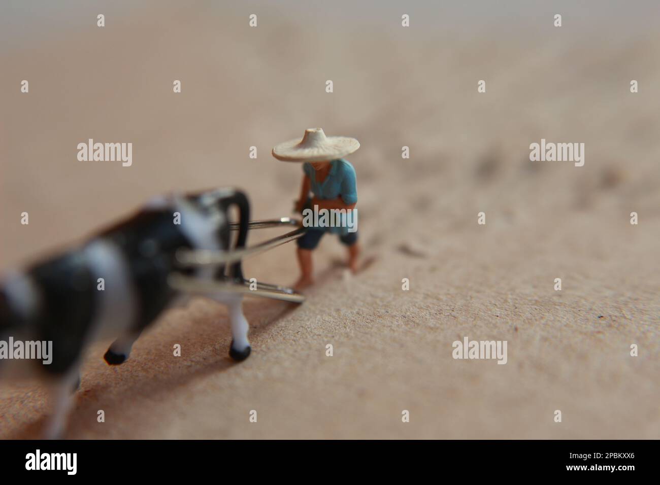 miniature figure of a farmer plowing a field with his cow on a ...