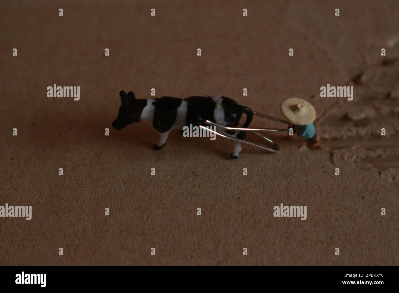 miniature figure of a farmer plowing a field with his cow on a ...