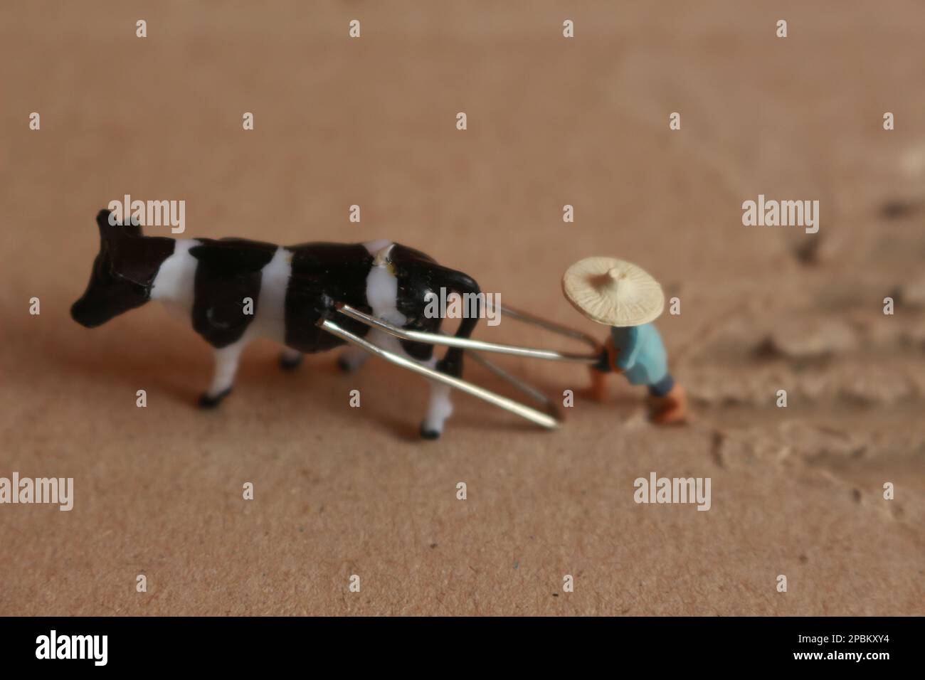 miniature figure of a farmer plowing a field with his cow on a ...