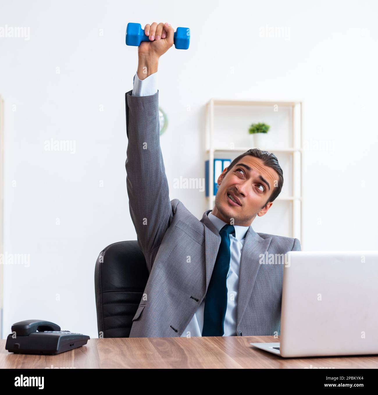 The young handsome employee doing sport exercises at workplace Stock ...