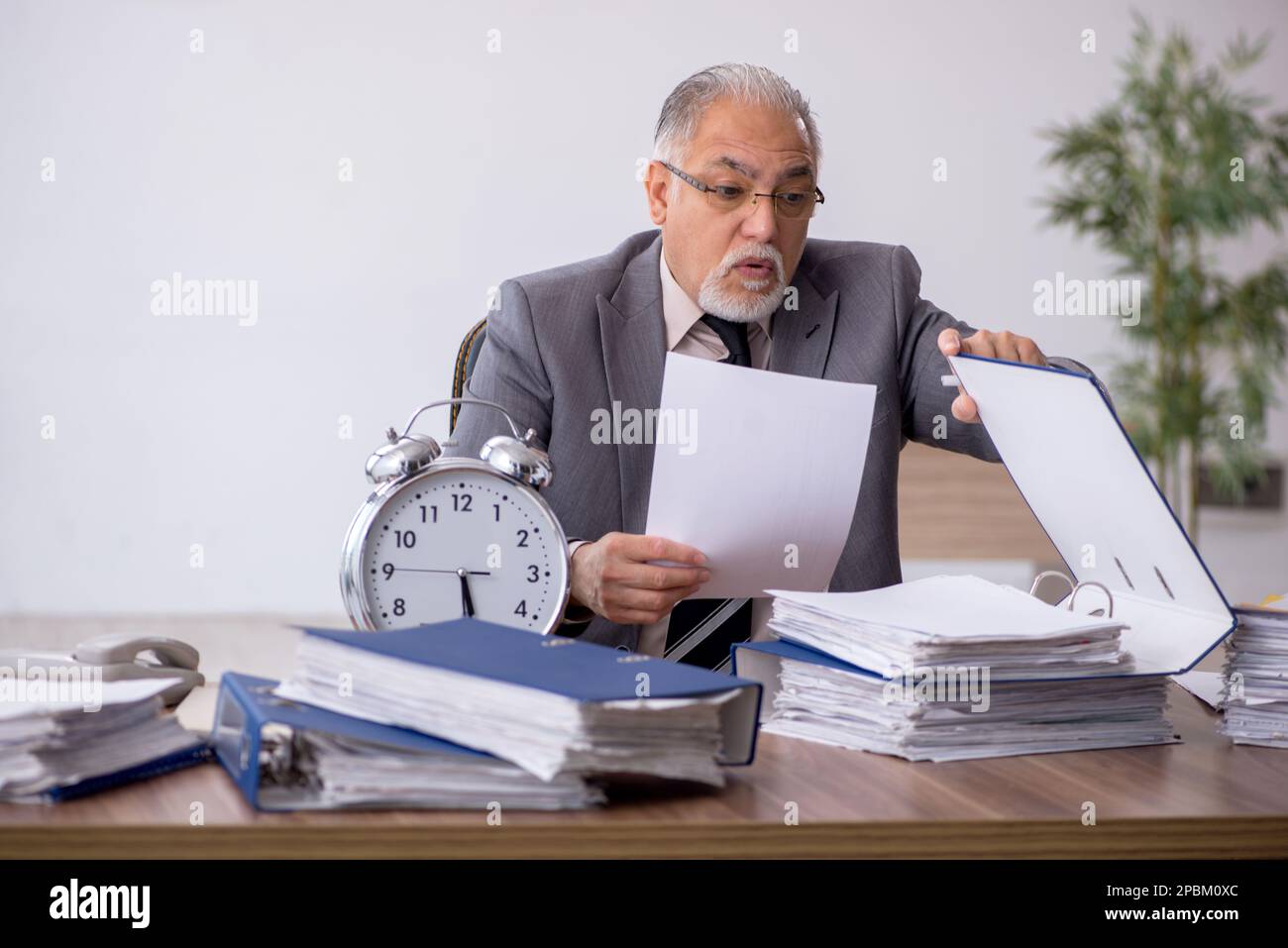 Old male boss in time management concept Stock Photo - Alamy