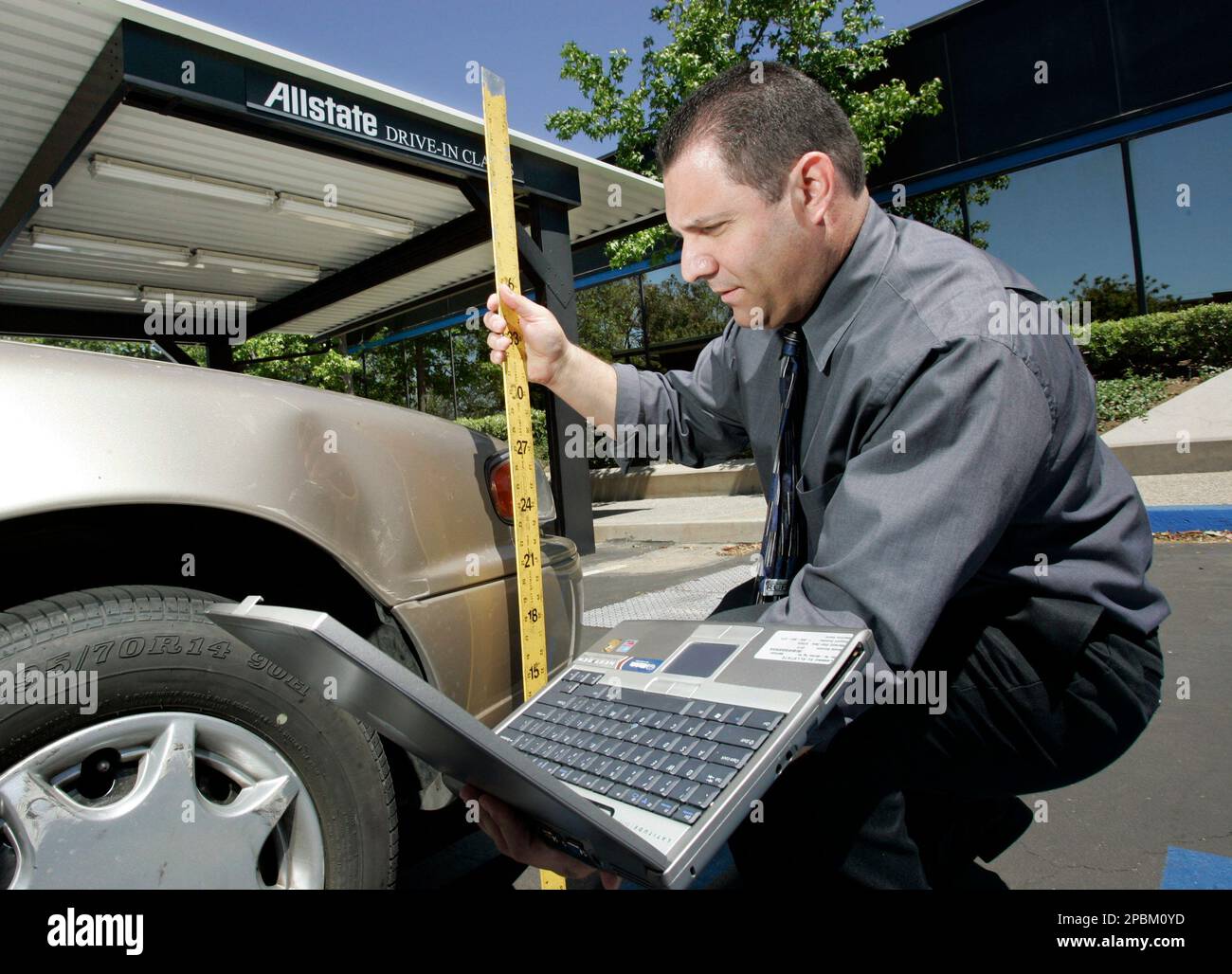 Claims adjuster Steve Schifter checks damage to an insured's car at an ...