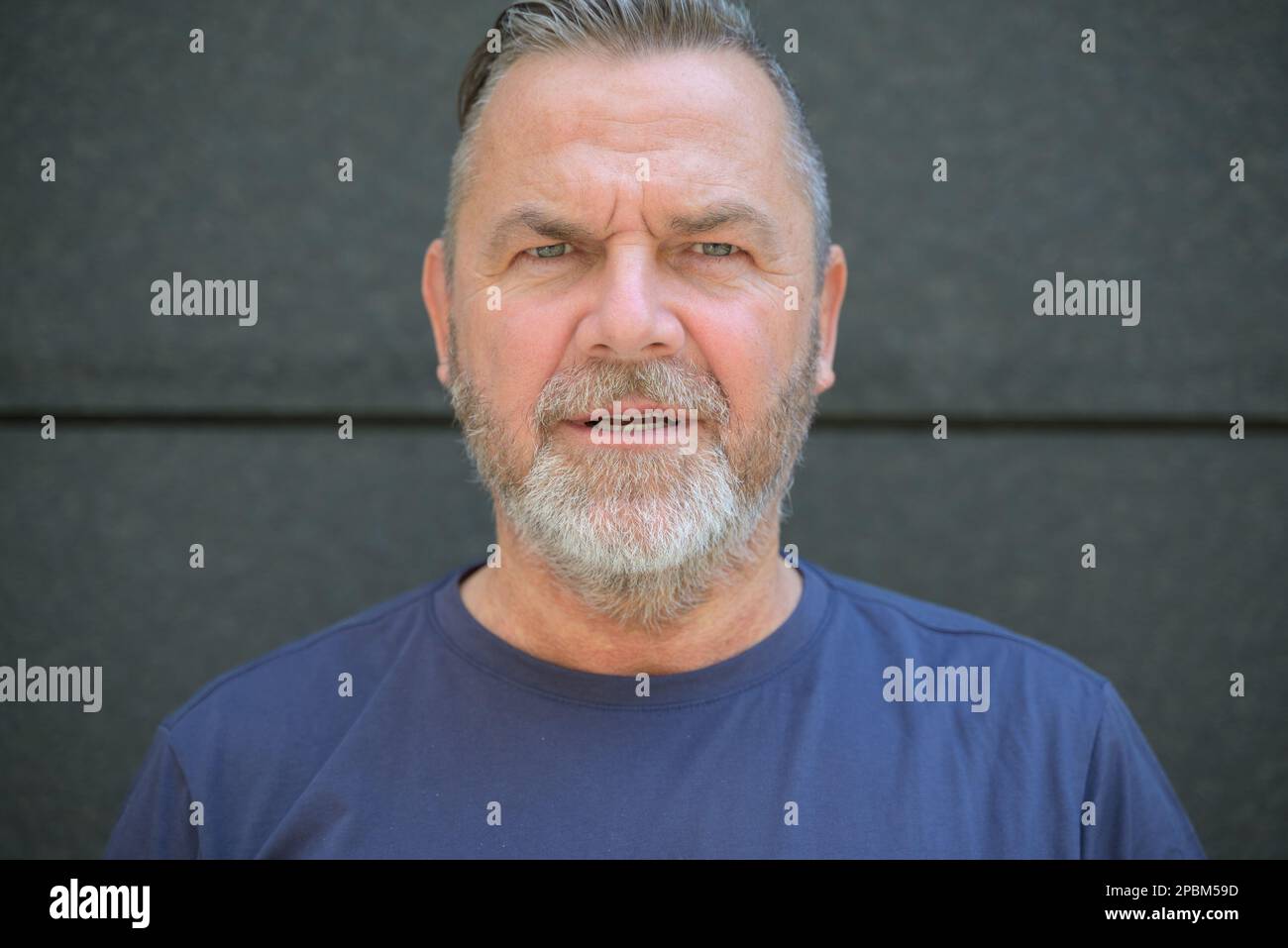 Bearded middle aged man staring at the camera in consternation ...