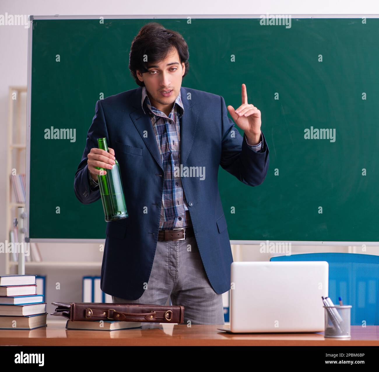 The male teacher drinking in the classroom Stock Photo - Alamy