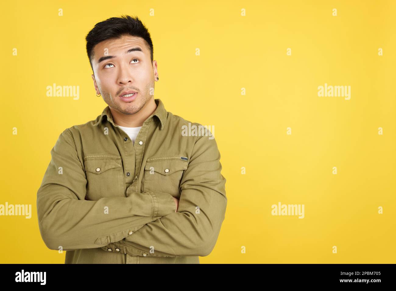 Bored chinese man looking up standing with arms crossed Stock Photo - Alamy