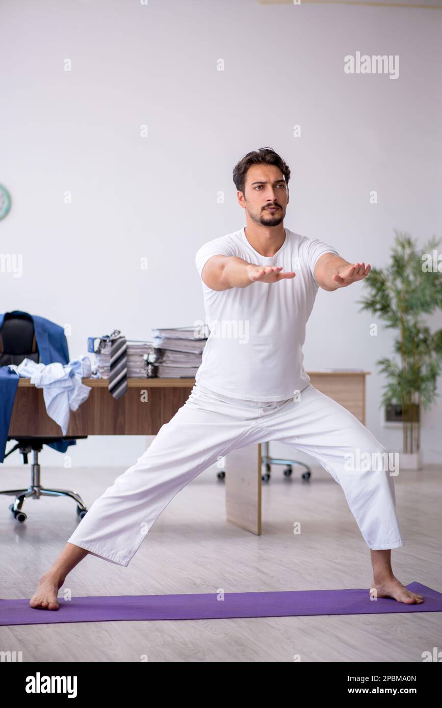 Young businessman employee doing sport exercises at workplace Stock ...