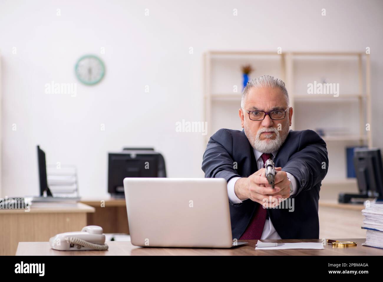 Old male employee holding gun at workplace Stock Photo - Alamy
