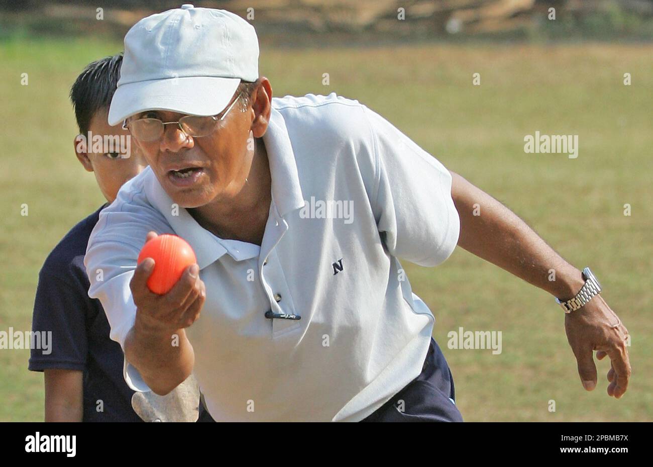 Cricket coach Michael Kyaw Min shows Zin Min Tun, 9, back, how to bowl ...