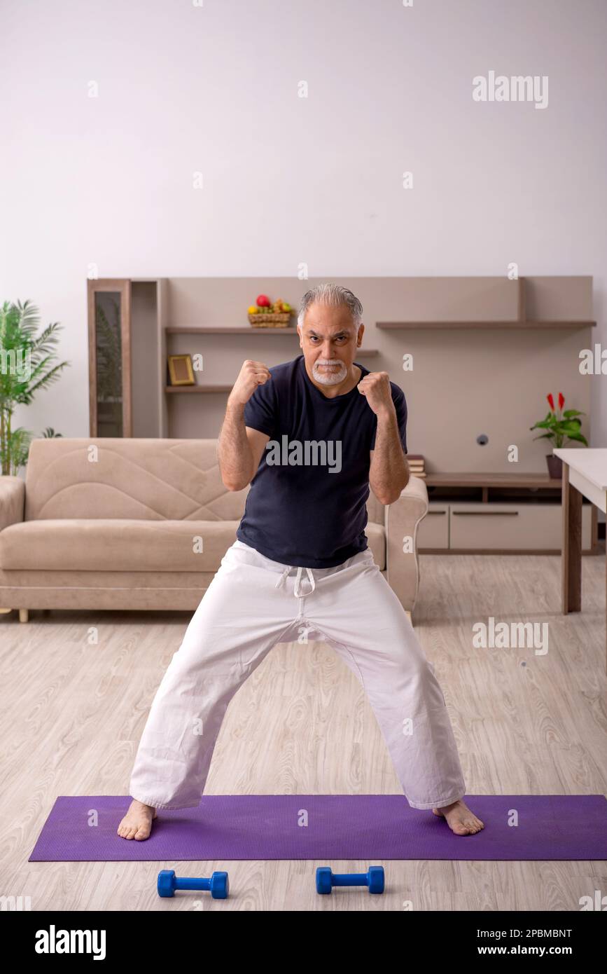 Old man doing sport exercises indoors Stock Photo - Alamy