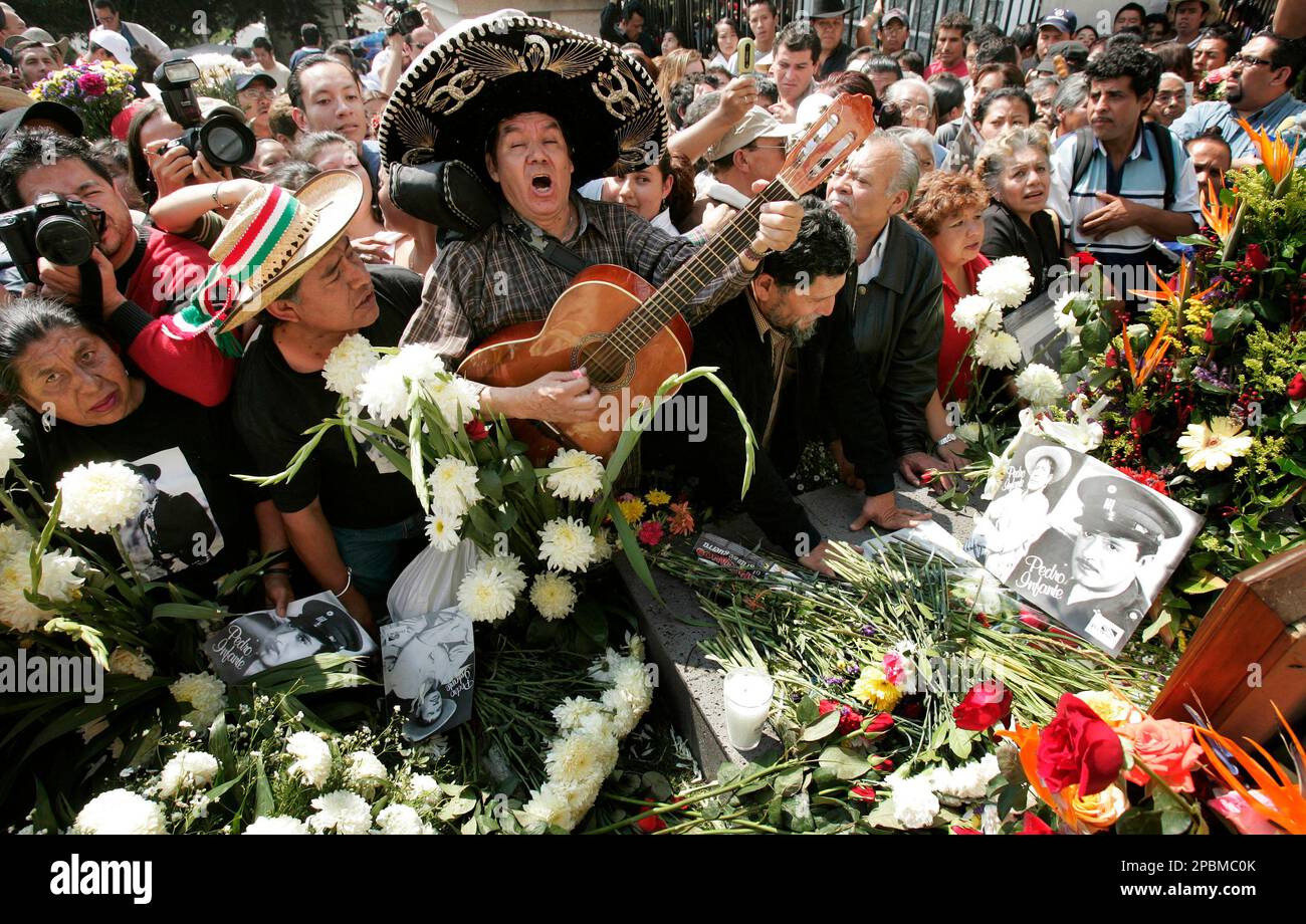 A man wearing a Mariachi hat sings surrounded by a crowd of visitors to ...