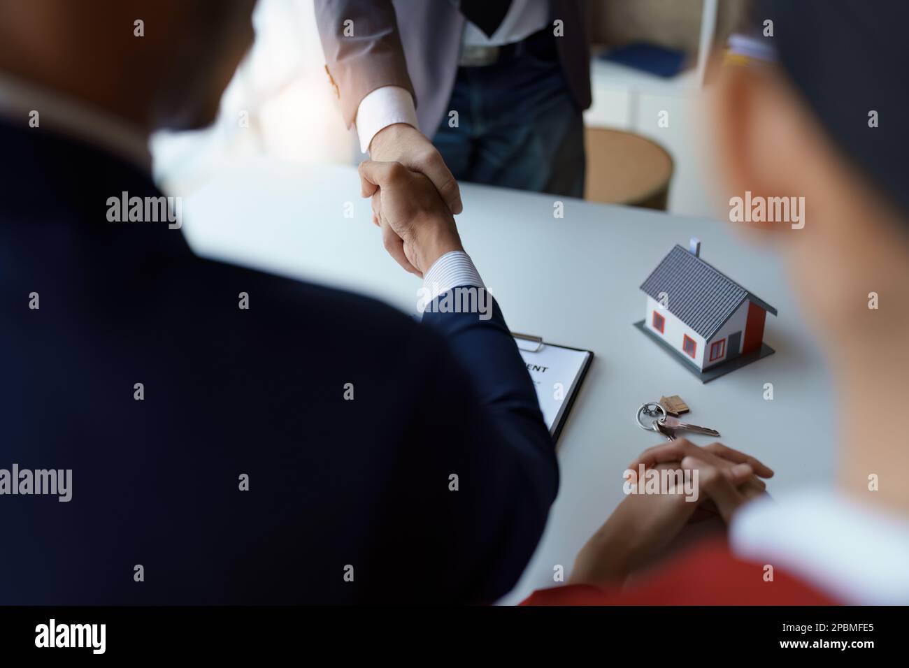 Asian real estate agent shaking hands handing over house and keys to ...