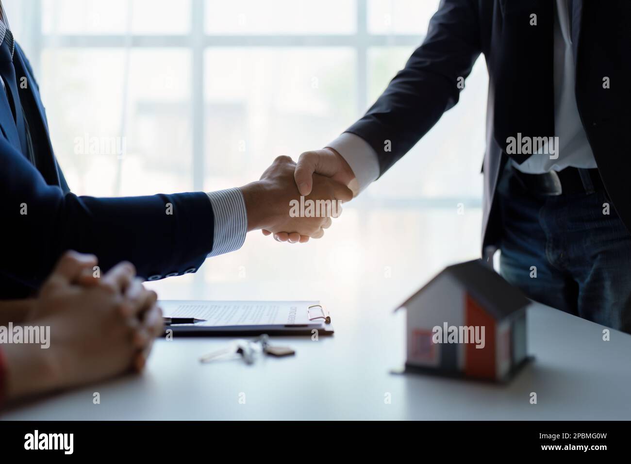 Asian real estate agent shaking hands handing over house and keys to ...