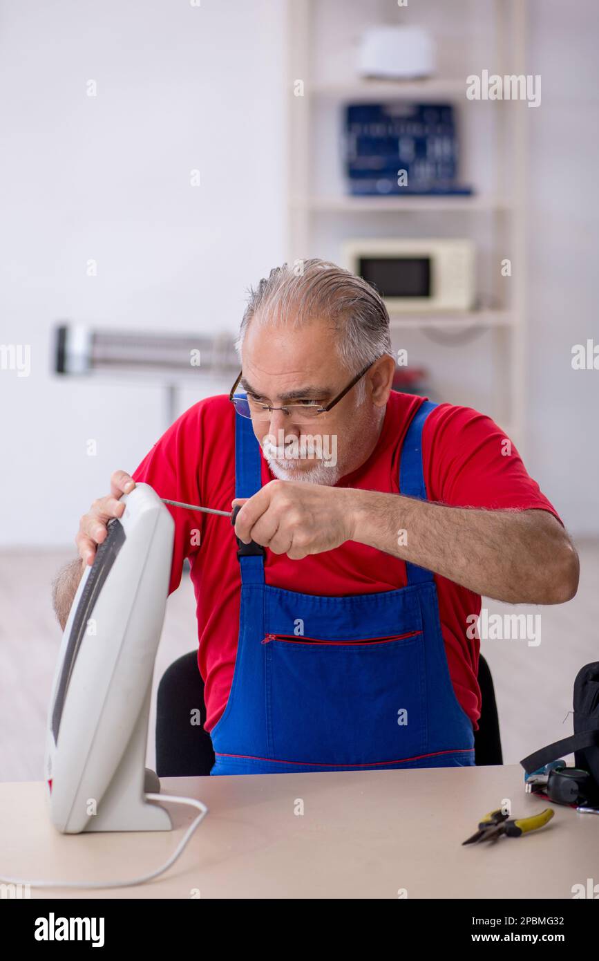 Old male repairman repairing heater at workshop Stock Photo - Alamy