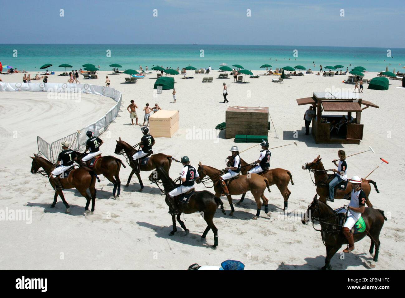 A parade of polo players enters the ring as beachgoers look on at the ...