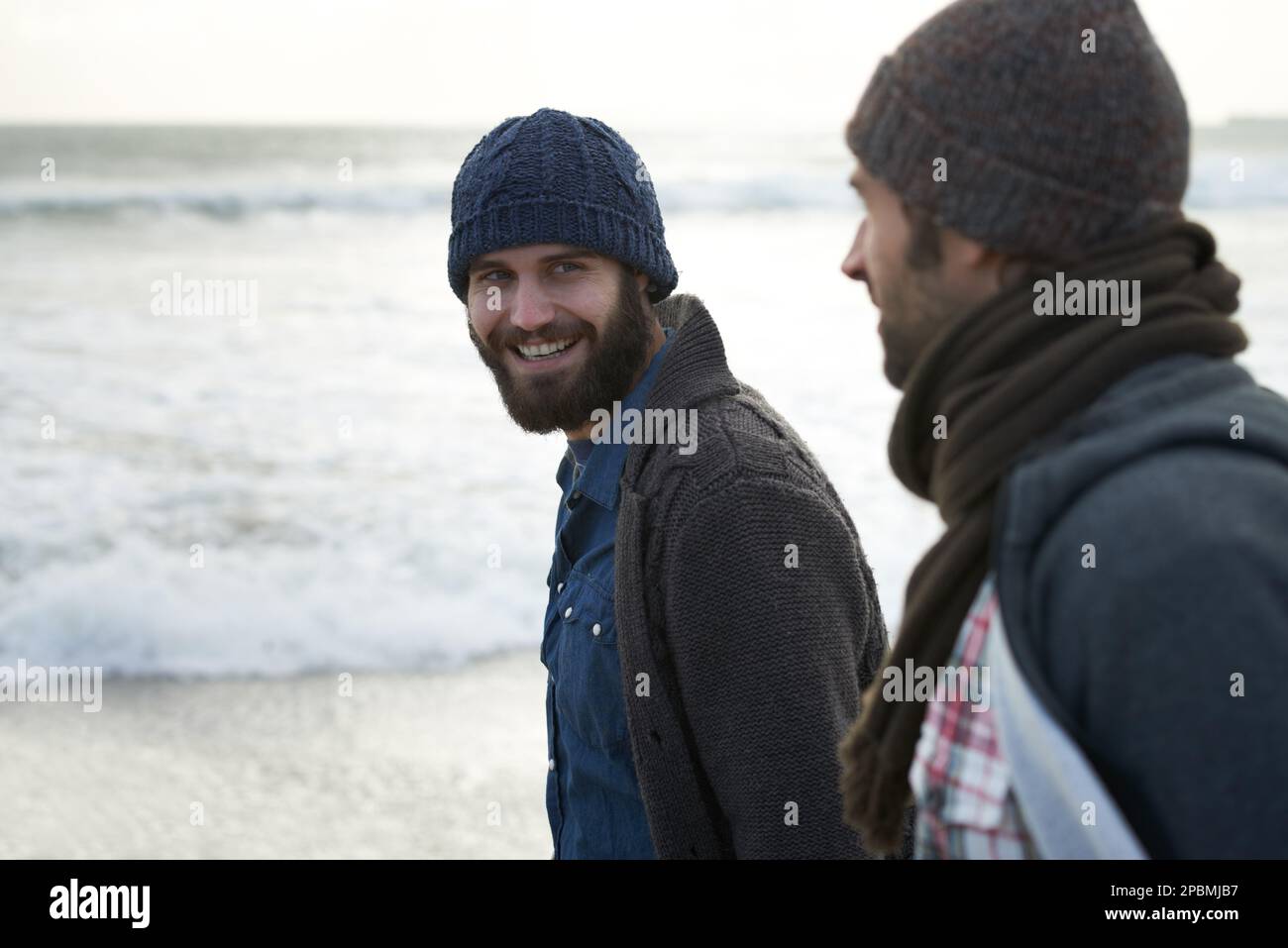 Fishing friends. Two young fishermen walking on the beach on an early ...