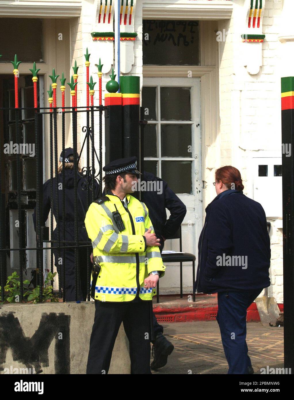 A police search team walks past a police officer standing at the gate ...