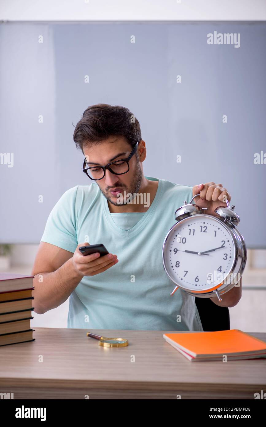 Young student in time management concept in the classroom Stock Photo ...