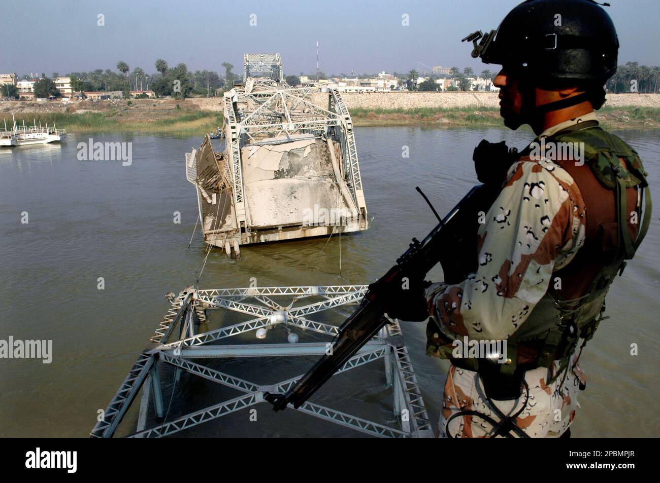 Iraqi soldier stands next to a collapsed bridge in Baghdad, Iraq ...