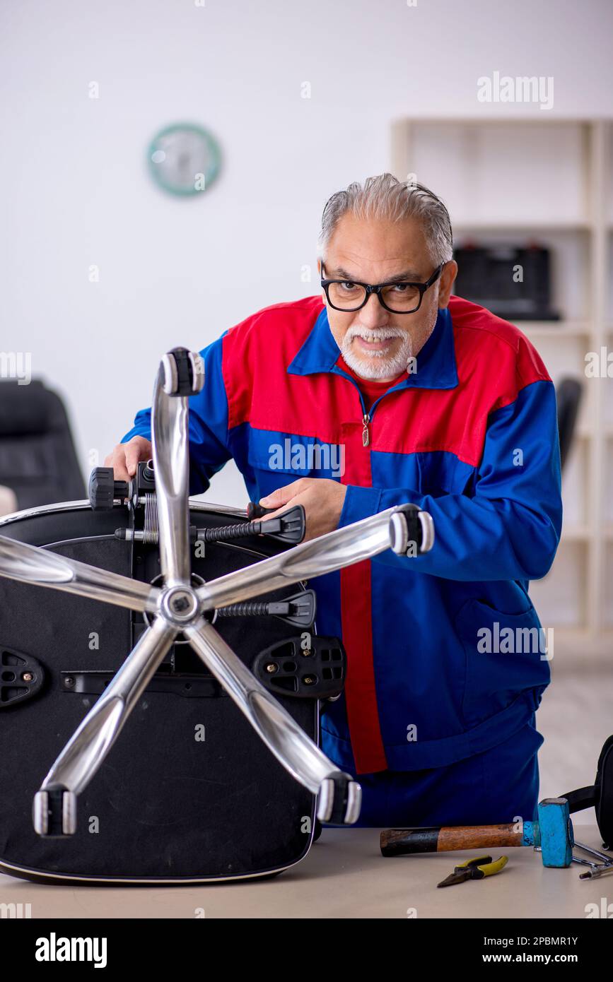 Old repairman repairing office chair Stock Photo - Alamy