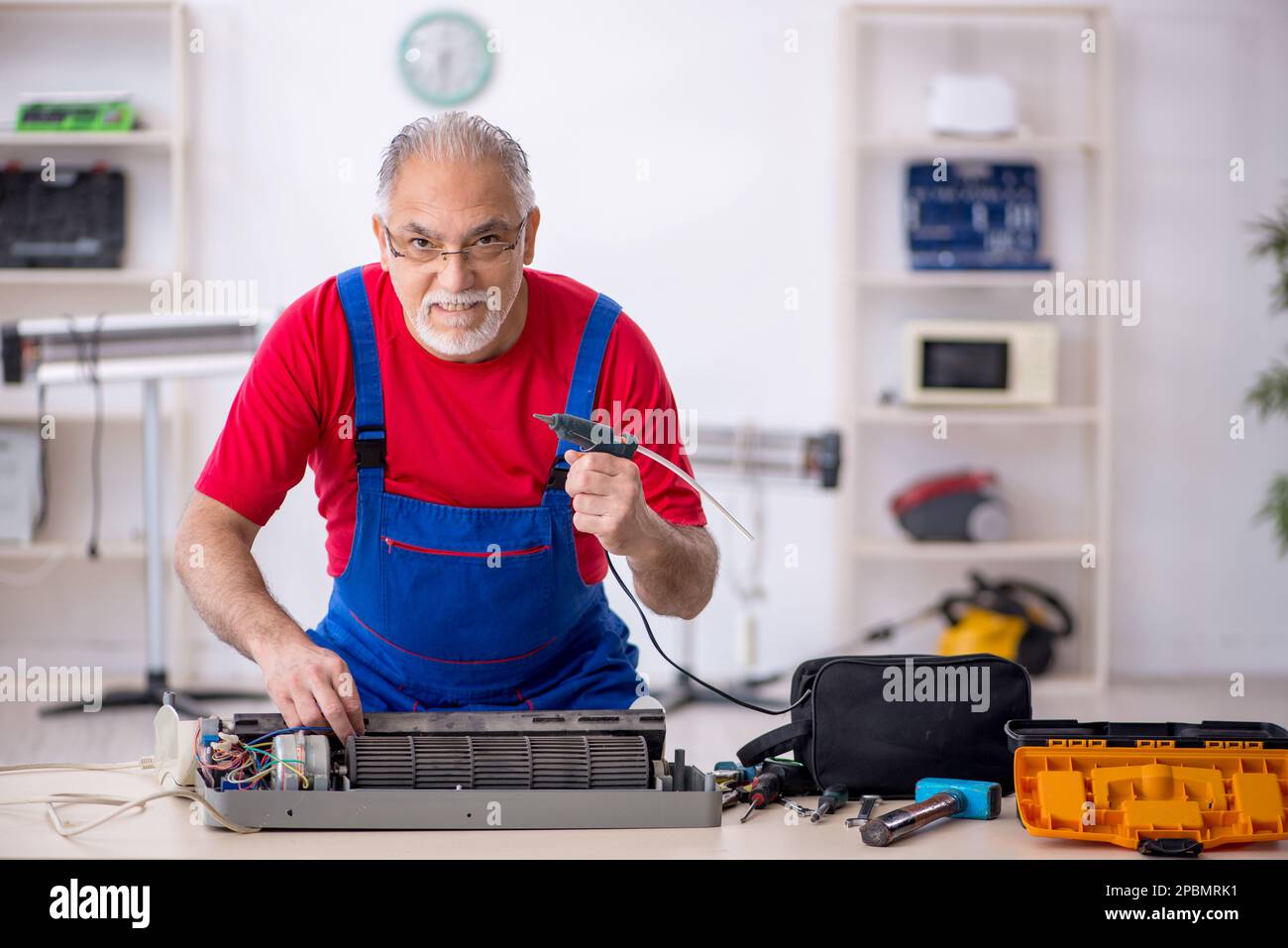 Old male repairman repairing air-conditioner Stock Photo - Alamy