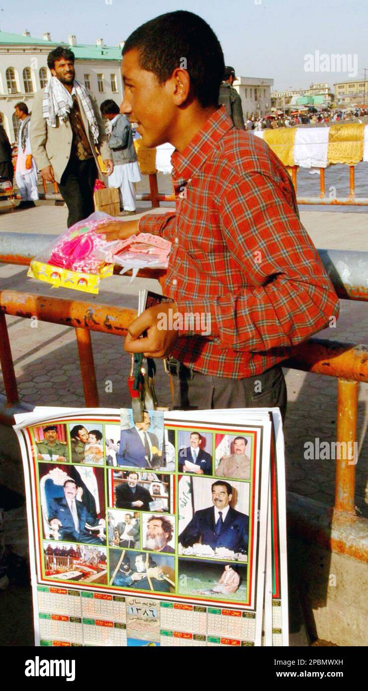 An Afghan boy sells a calendar filled with pictures of former Iraqi ...