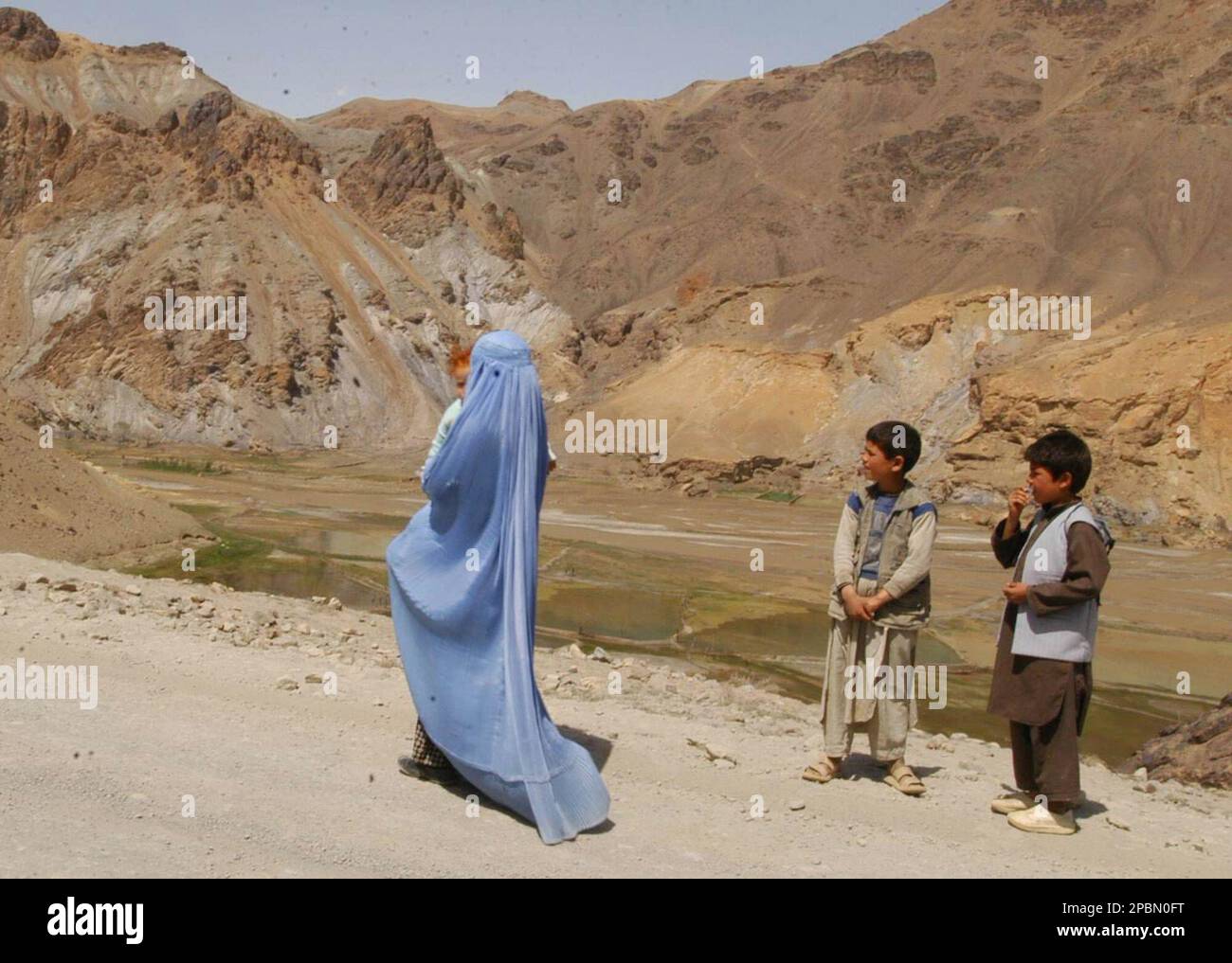 An Afghan women wearing a traditional all-enveloping burqa walks with ...