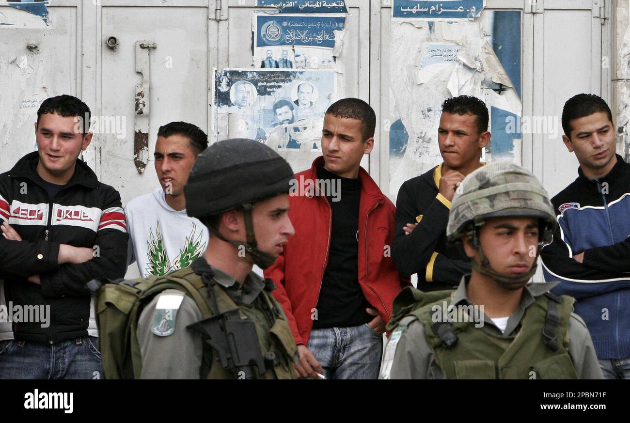 Israeli border police stand guard as Palestinians wait during a routine ...