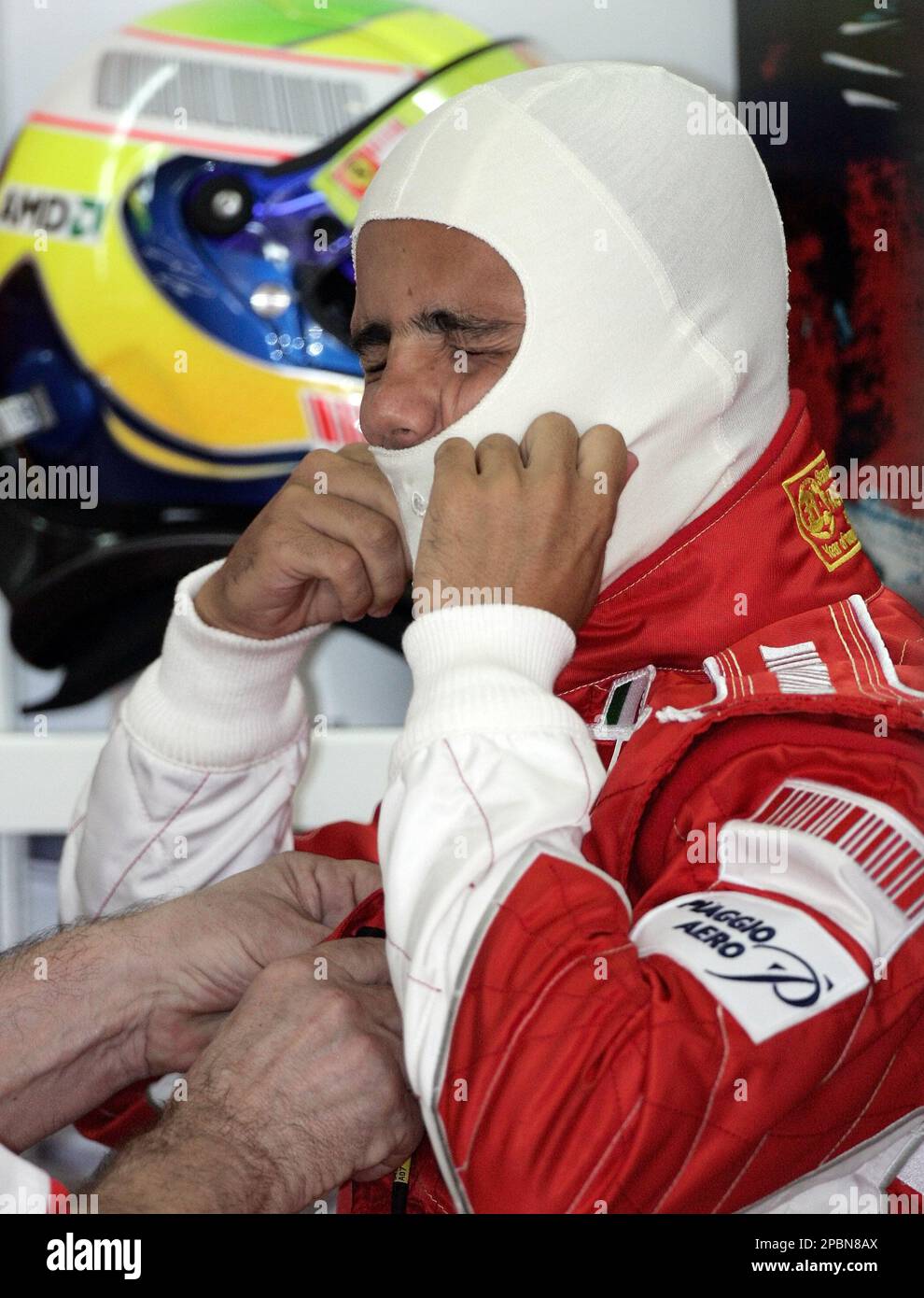 Brazilian Ferrari driver Felipe Massa is helped to wear his racing suit ...