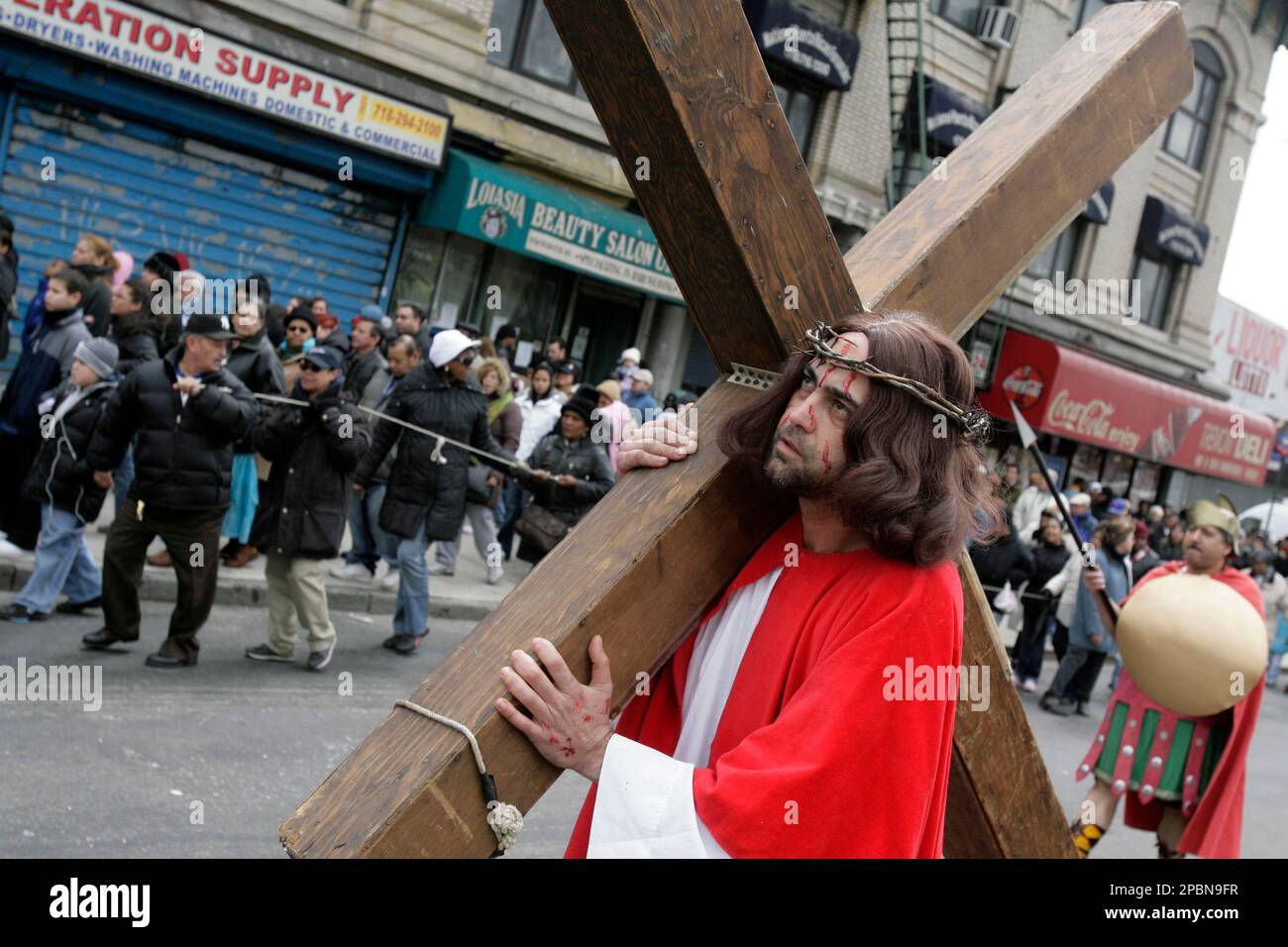 Jesus Christ, played by Rafael N. Gonzalez, drags a cross through the ...