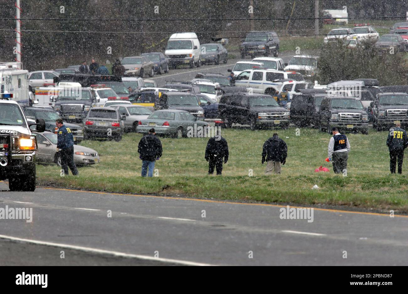 FBI agents walk in a line in a snow squall, as they look for evidence ...