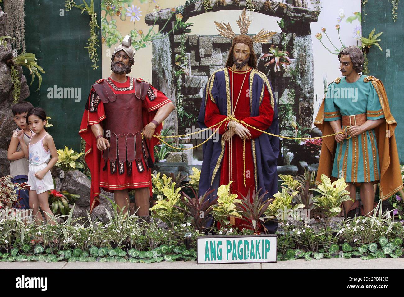 Filipino kids play beside lifesize images of Jesus Christ and his ...