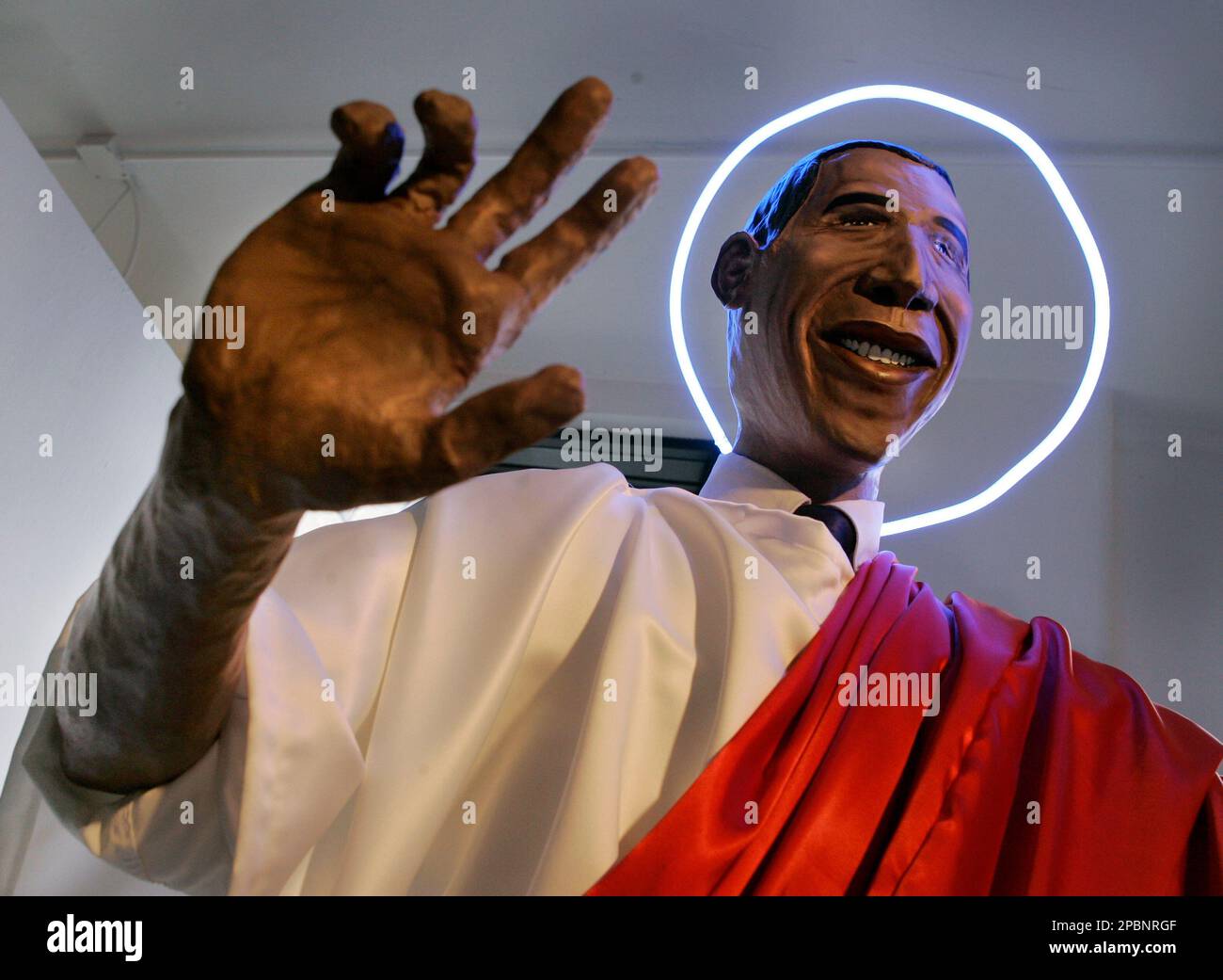 A smiling, life-sized sculpture of Barack Obama with a blue neon halo ...