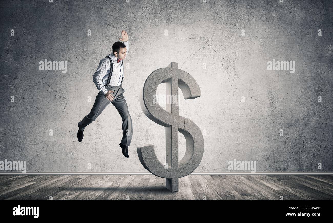 Determined banker man in empty concrete room breaking dollar figure ...