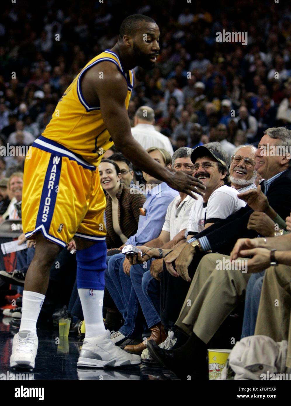 Golden State Warriors' Baron Davis, left, checks on the condition of Warriors owner Chris Cohan ...
