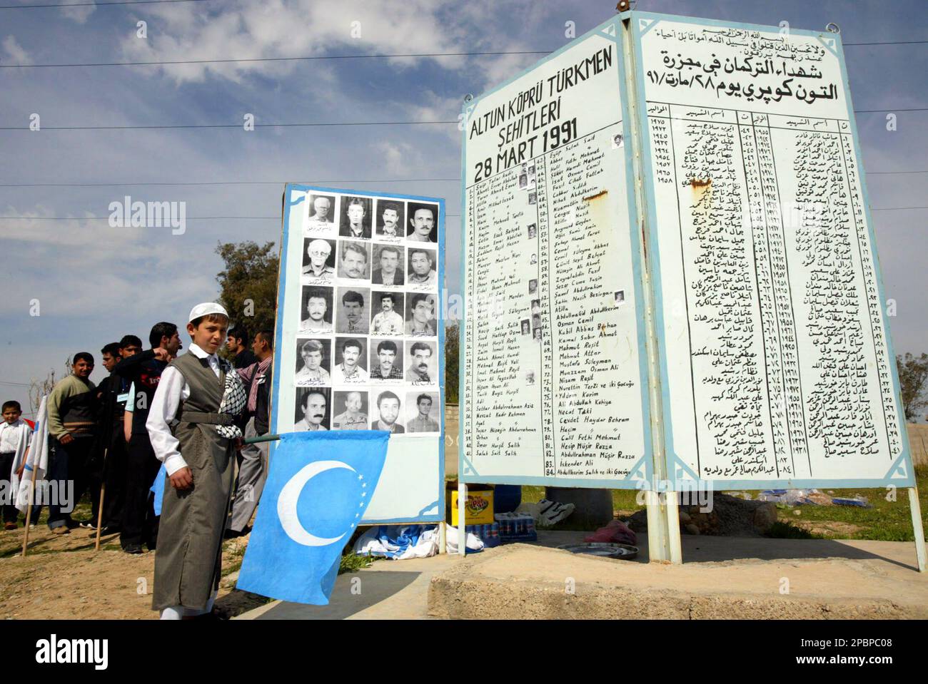 Turkmens stand by a memorial bearing the names of members of their ...