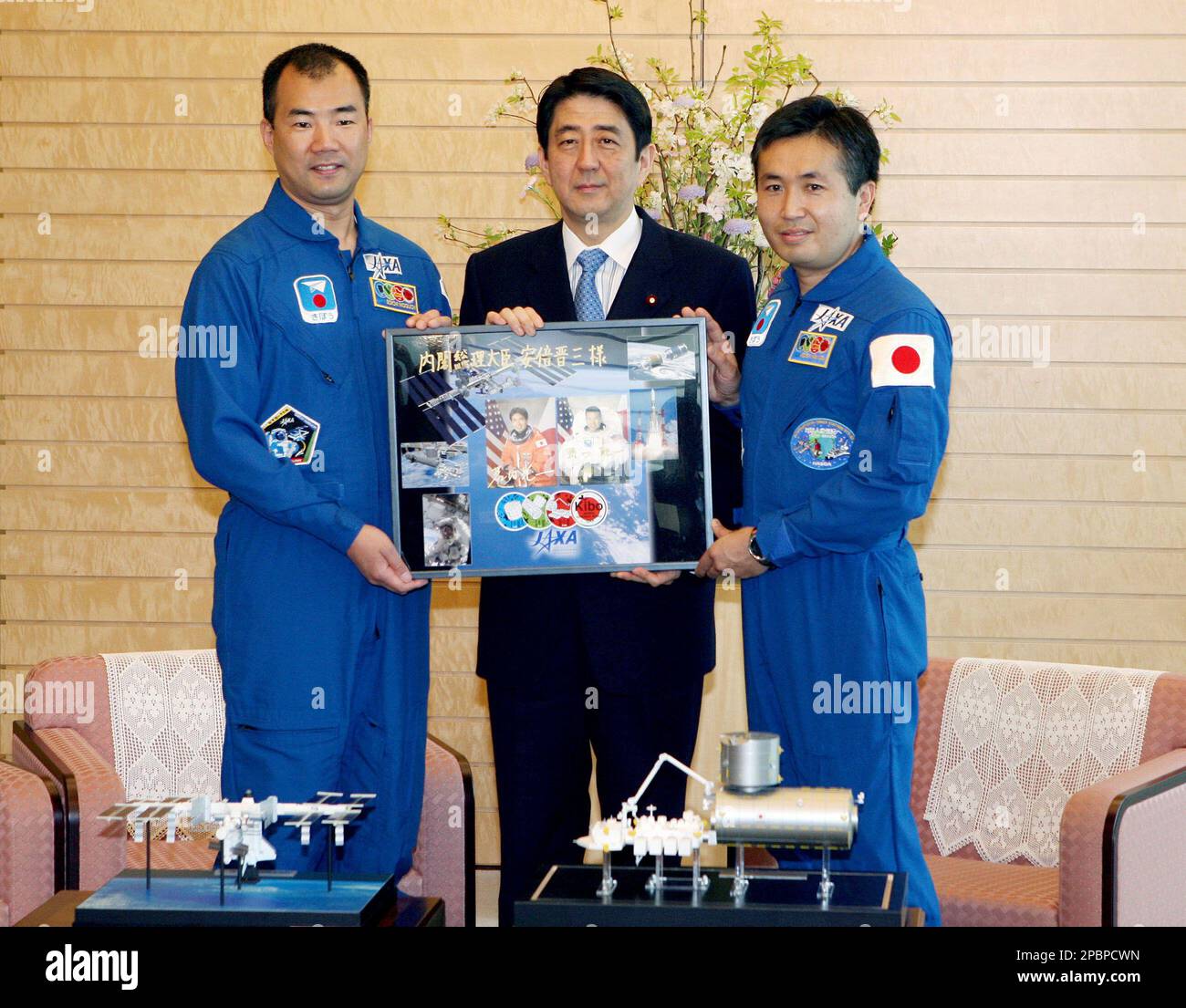 Japanese Prime Minister Shinzo Abe, center, holds a commemorative photo of Japanese astronauts ...