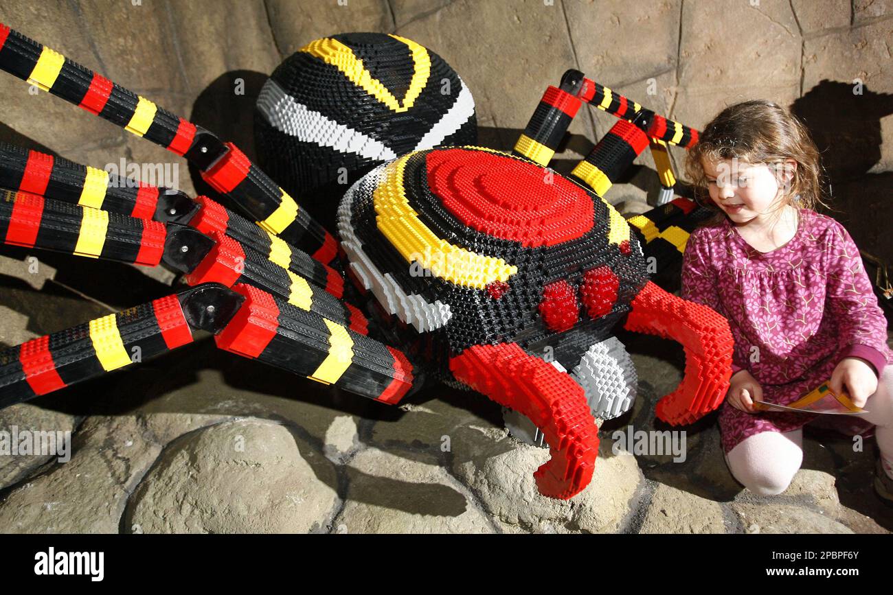 A little girl looks at a giant spider made of Lego bricks during the ...