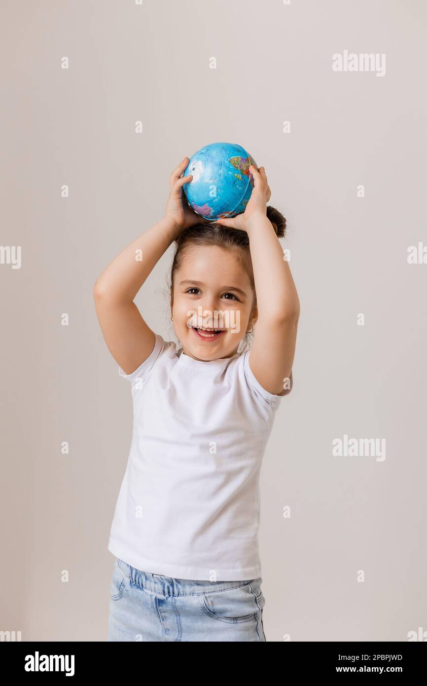 a happy little girl is holding a small globe planet in her hands in a ...