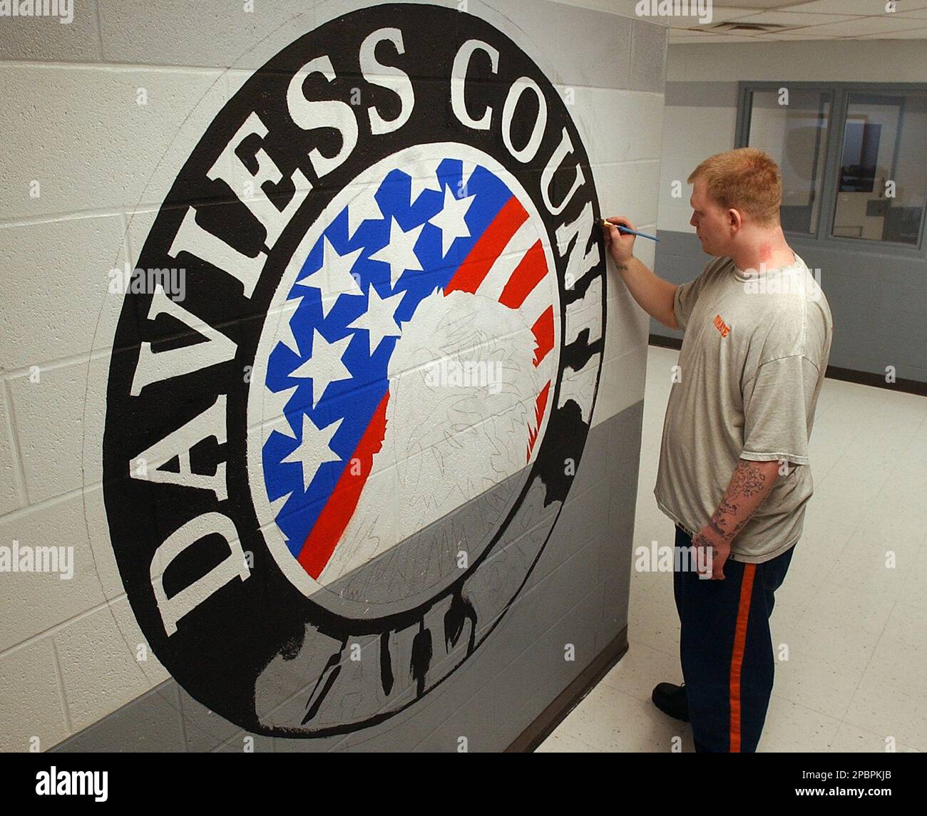 Rob Penrose carefully cuts around the lettering while painting a mural ...