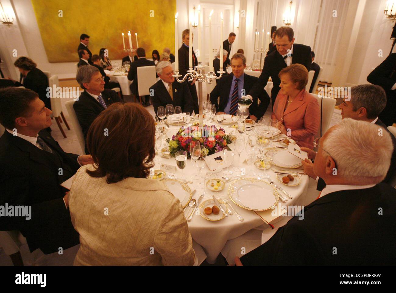 A waiter pours a glass of wine between German Chancellor Angela Merkel ...