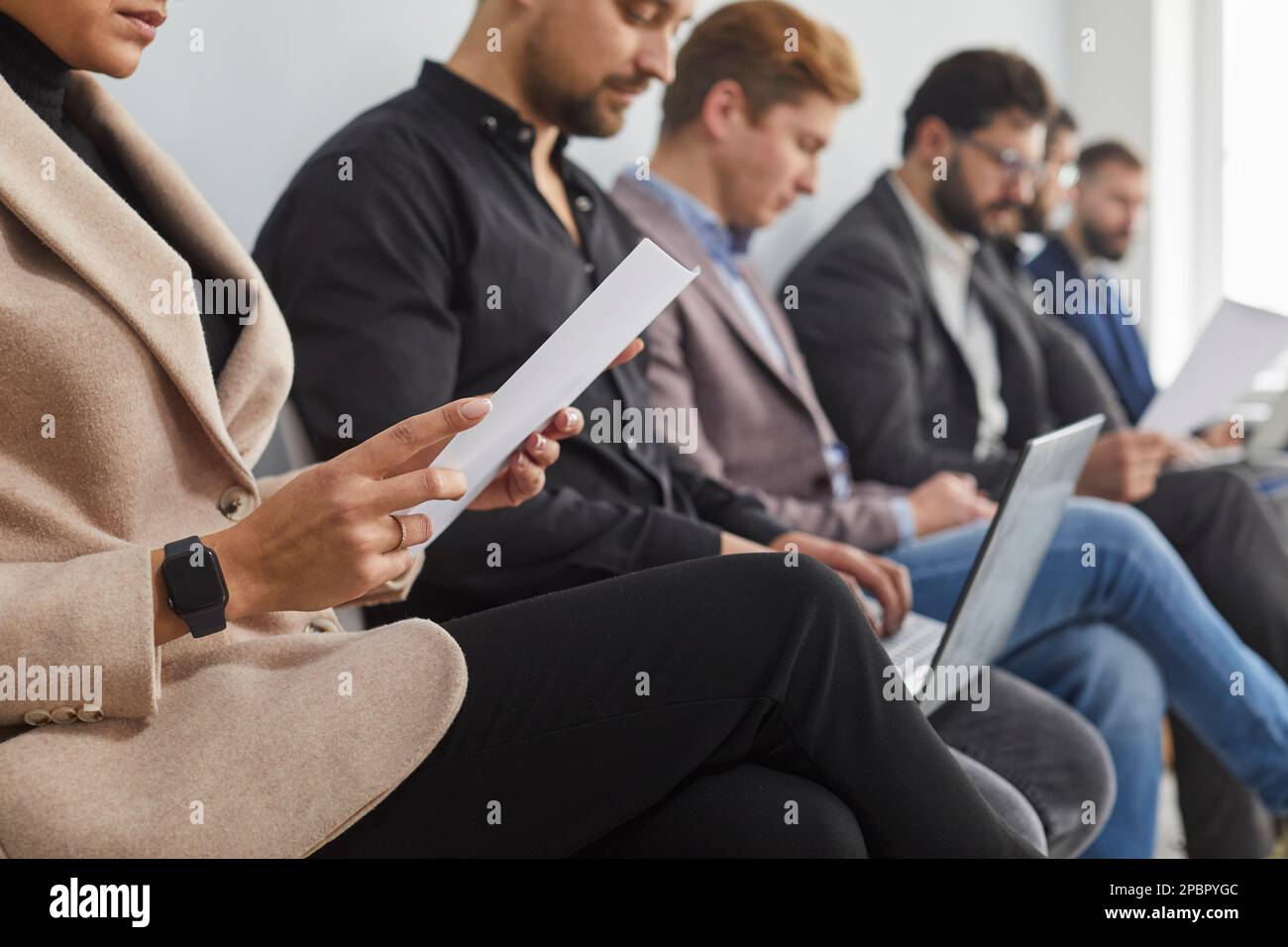 Group of candidate are sitting on chairs in a queue, waiting for an ...