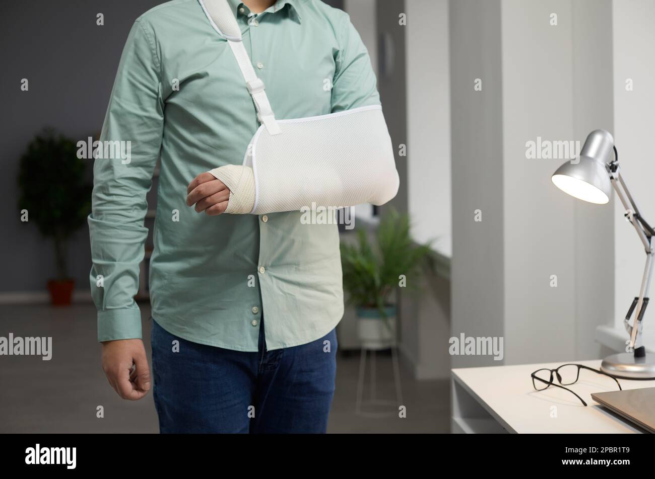 Close-up of the middle part of man with broken bandaged arm in cast ...
